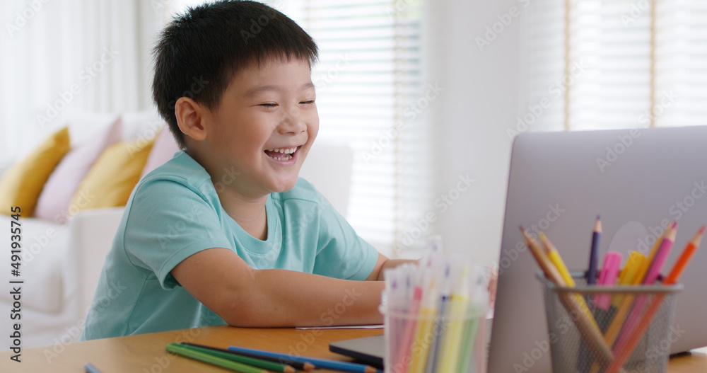 Cute pupil child gen z alpha boy sit talk video call self e-learning lesson on laptop at home ...