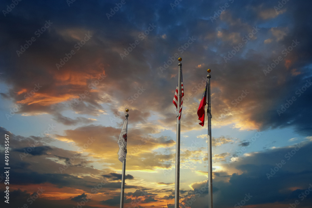 a stunning share of an American flag and two other flags flying on tall ...