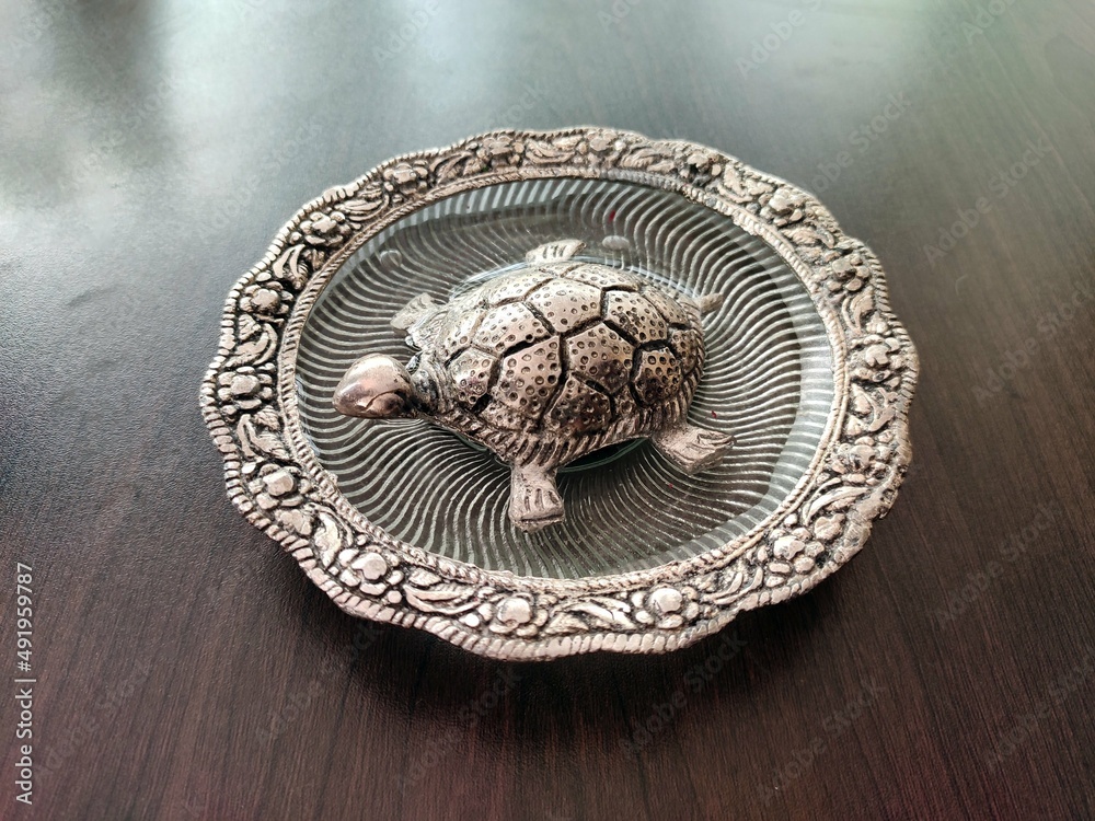 Silver tortoise on a plate for Vastu at home and office. It is believed ...
