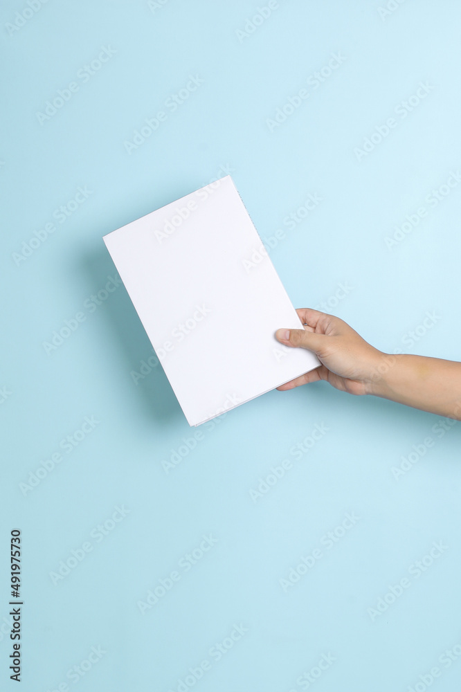 Hand holding book isolated on blue pastel background for book mock up ...