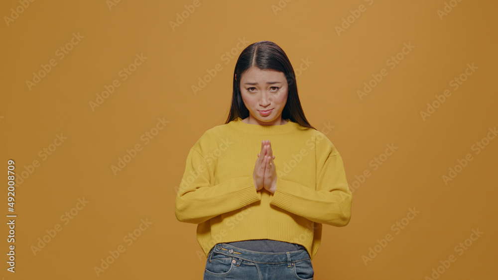 Asian woman doing praying gesture with hands and begging in front of ...