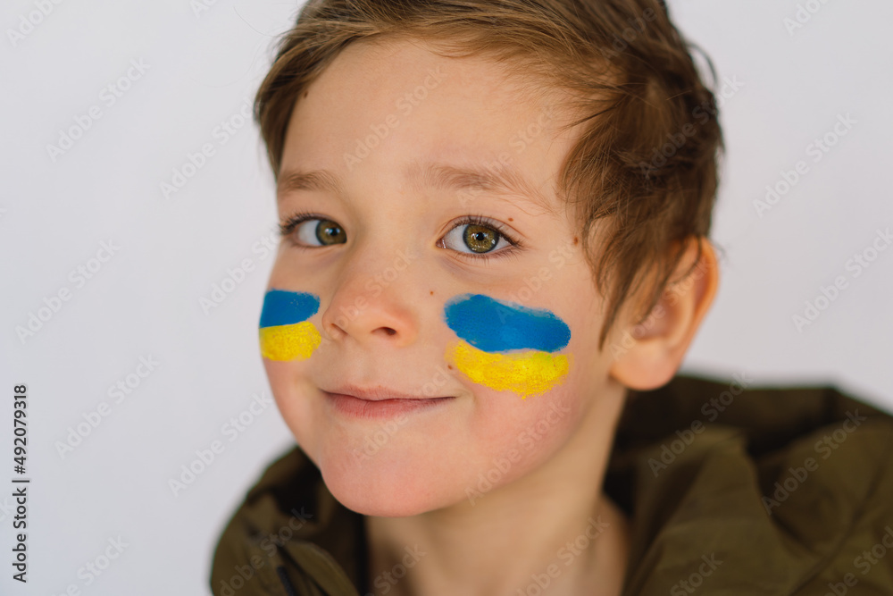 Portrait of a Ukrainian boy with a face painted with the colors of the ...