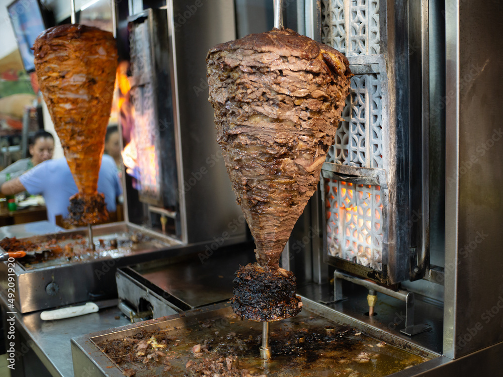 Meat on a spit. Kebab. Traditional street food of Mexico, Turkey. Meat ...