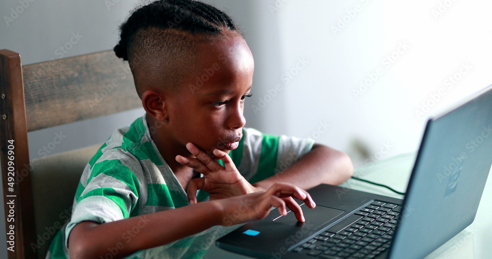 Little boy browsing internet on laptop. Black African ethnicity kid ...