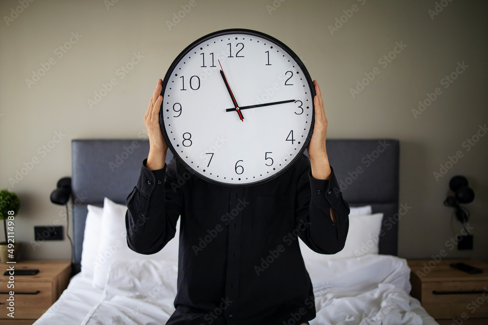 man holding big clock in bedroom, hiding, checking time on clock ...