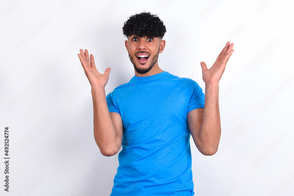 Crazy outraged young arab man with curly hair wearing blue t-shirt over ...