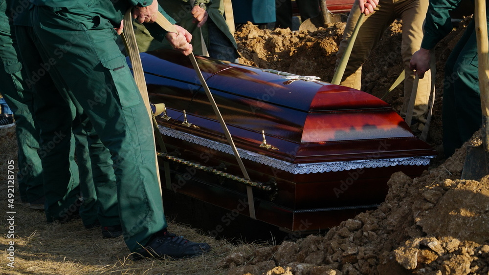 Religion, death and dolor - coffin bearer carrying casket at funeral to ...