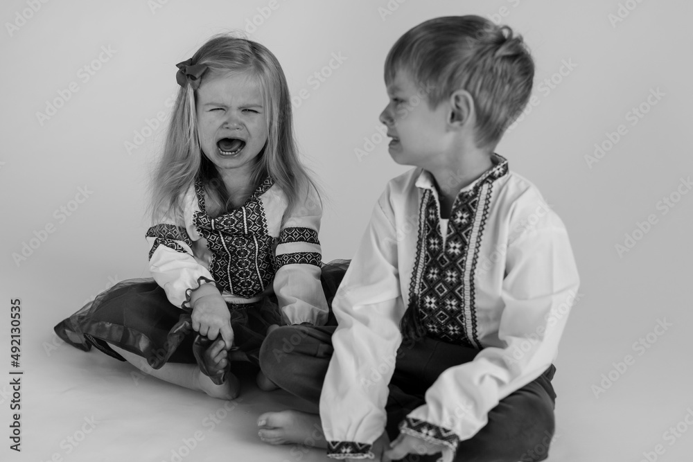 Two little children, boy and girl, crying over white background ...