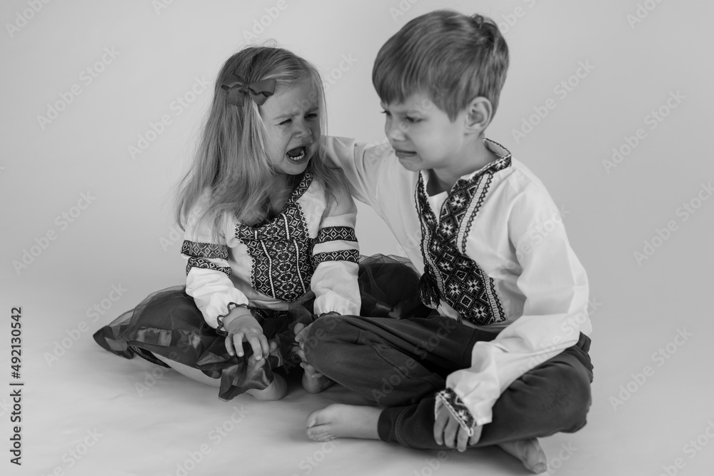 Two little children, boy and girl, crying over white background ...