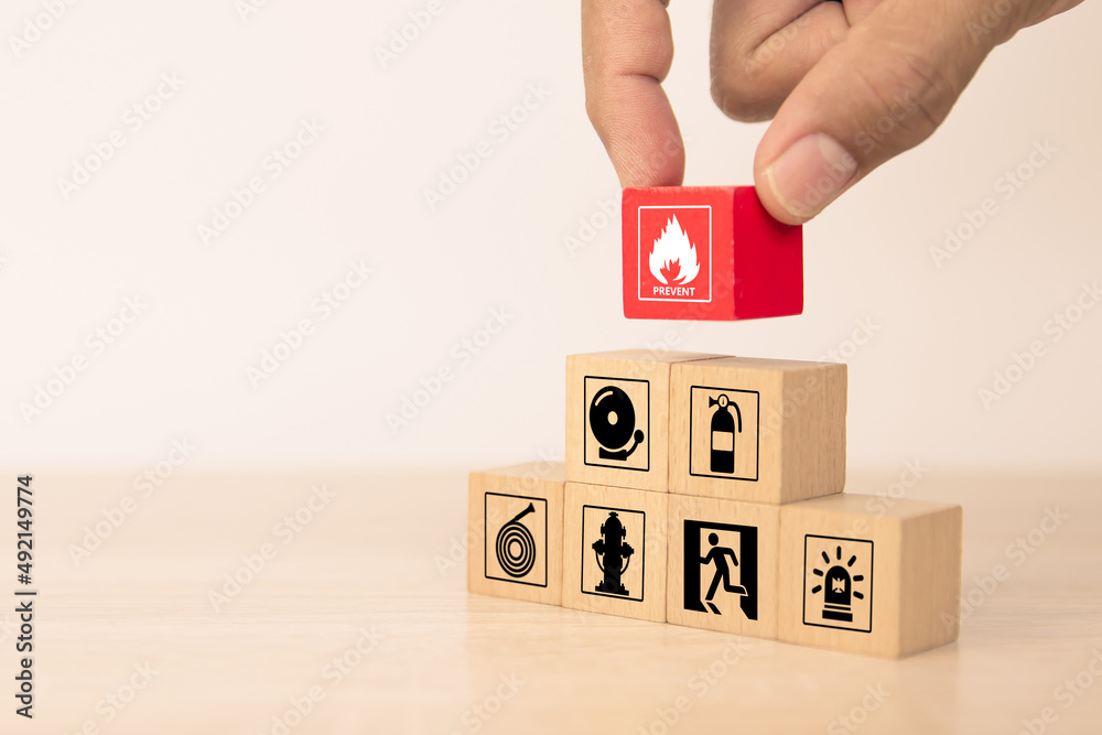 Hand choose cube wooden block stack with fire icon and door exit sing ...