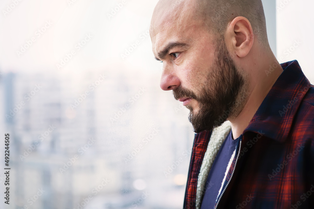 Portrait of a brutal bald man with a beard, he looks thoughtfully out ...