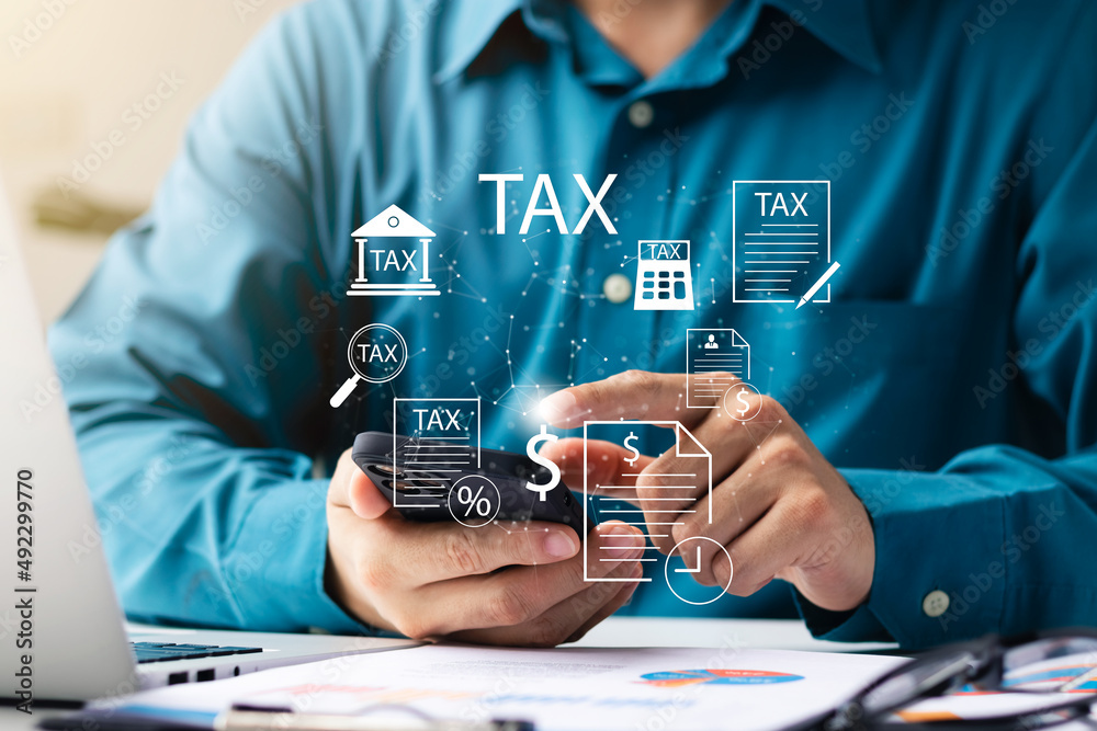 Businessman using his laptop computer and smartphone to fill out online ...