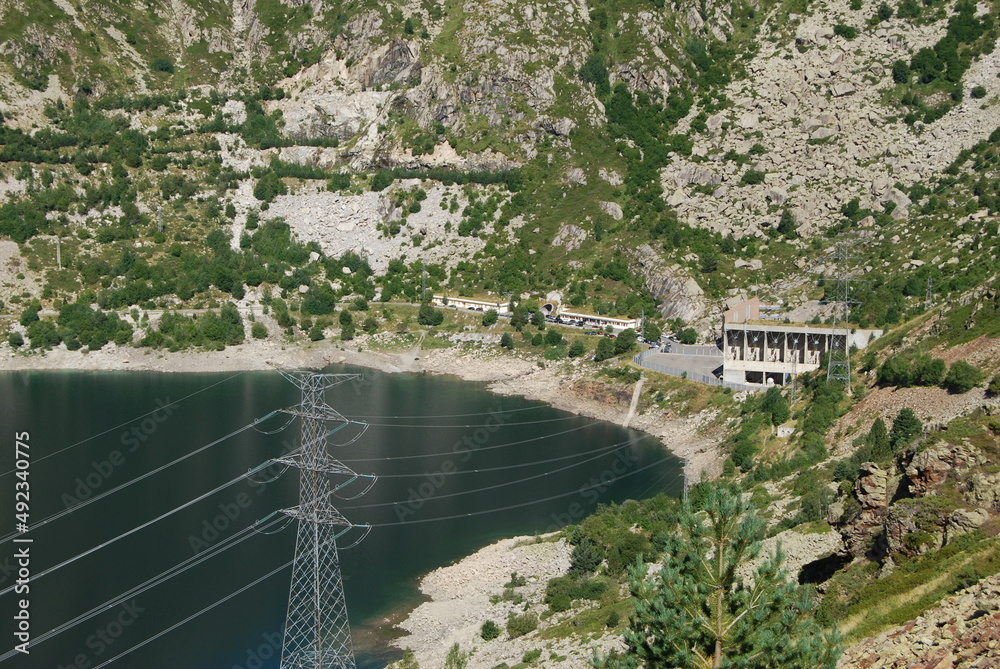 imagen de un lago entre montañas con unos cables eléctricos en el ...