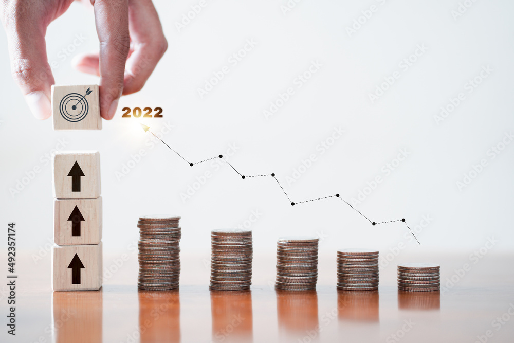 2022. Hand putting wooden cube box target board with stack coins on ...