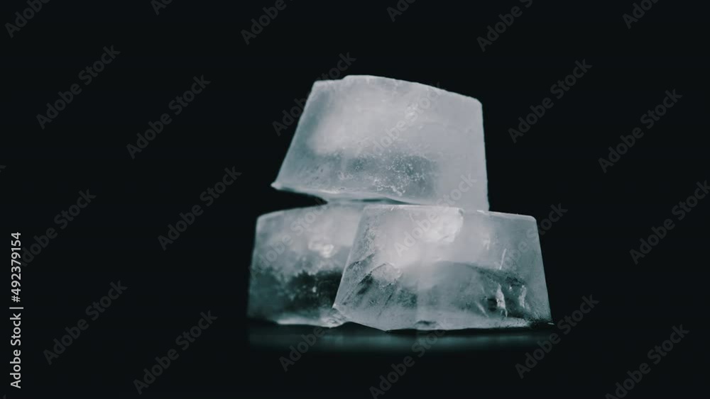 Square ice cubes are spinning on a black background. Water freezing in ...