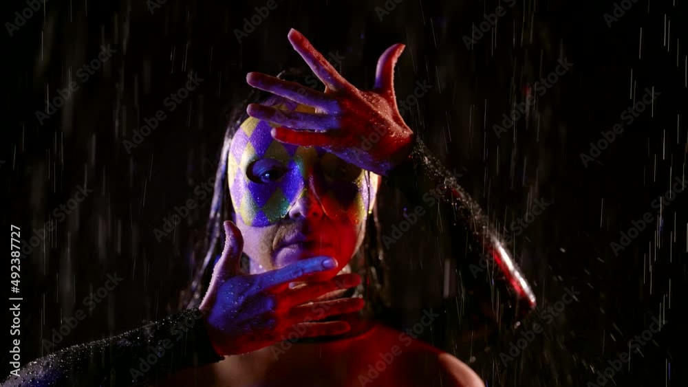 Close-up portrait of a masked woman in the rain her face is touched ...