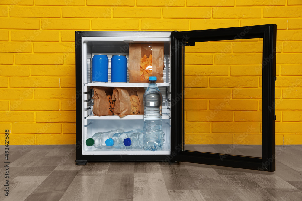 Mini bar filled with food and drinks near yellow brick wall indoors ...