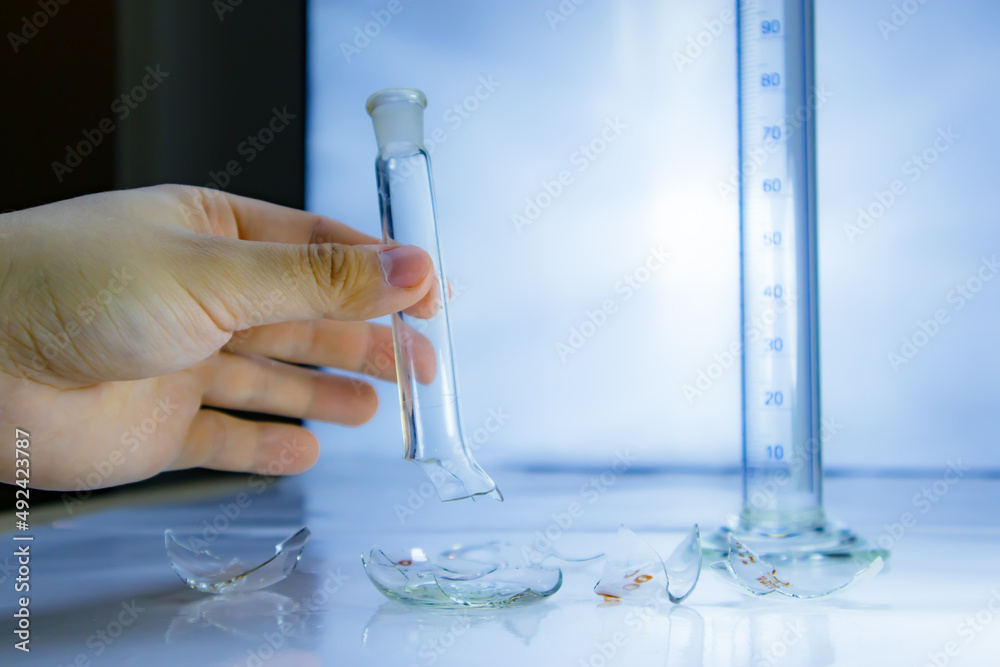Lab measurement glass and hand holding a broken lab flask. Failed lab ...
