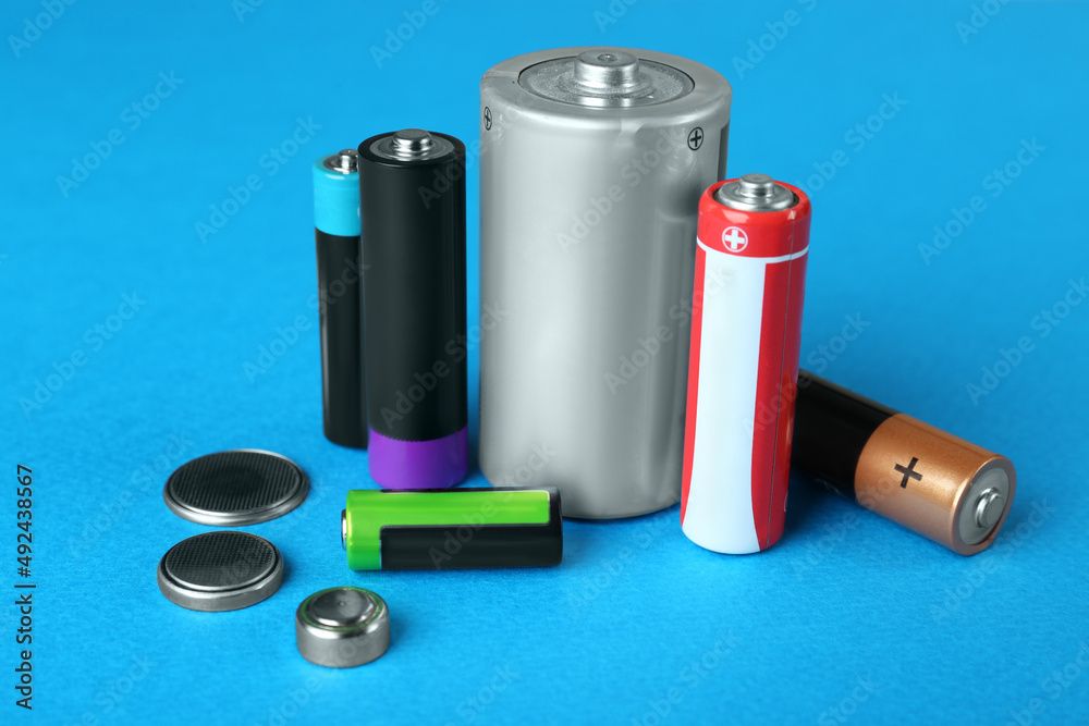 Different types of batteries on light blue background Stock Photo ...