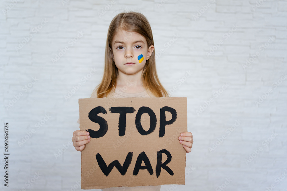 Upset toddler girl protesting war conflict raises banner with ...