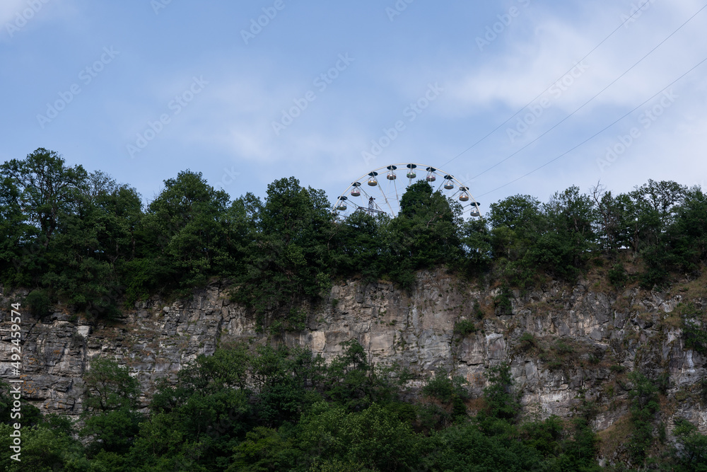 blue sky and a large rock cliff overgrown with green mounds and a ...