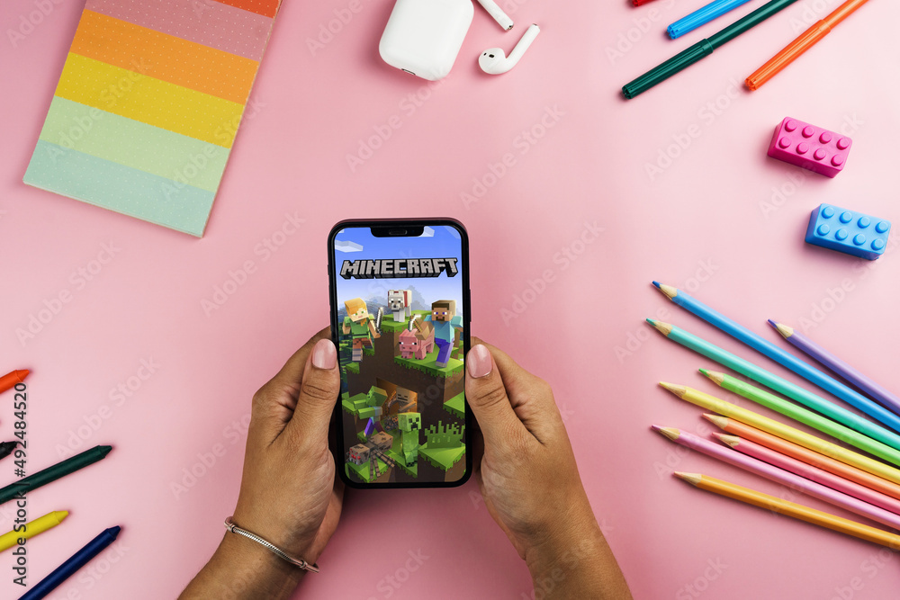 Girl holding a smartphone with Minecraft mobile game app on the screen ...