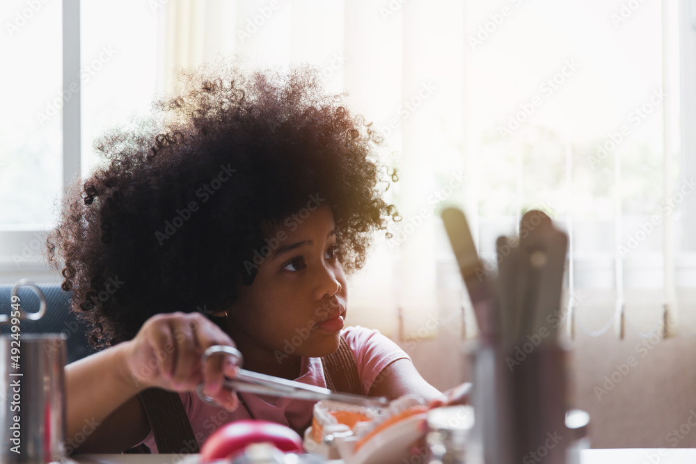 Little african girl holding an artificial model of human jaw with ...