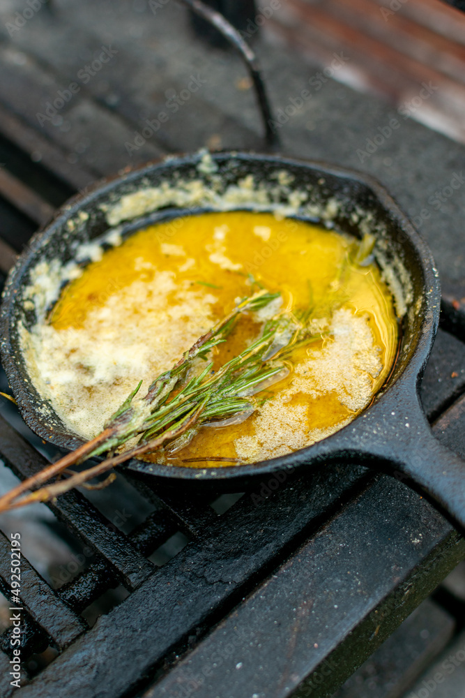 mantequilla derretida con romero en sarten de hierro sobre la parrilla ...