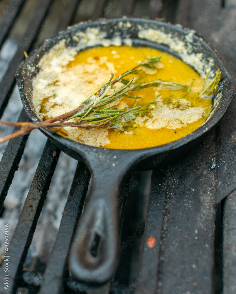 mantequilla derretida con romero en sarten de hierro sobre la parrilla ...