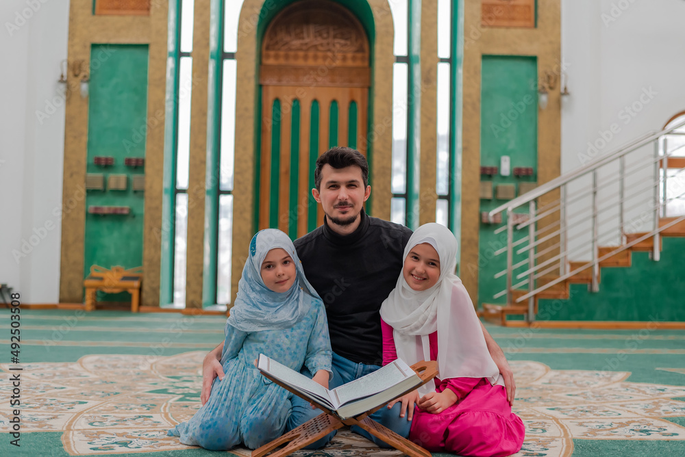 Happy Muslim family reading a holy book Quran in the mosque. Father ...