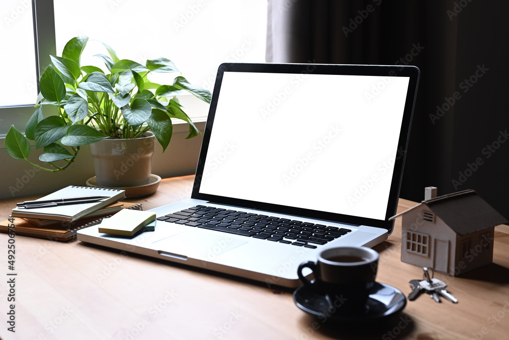 Mockup laptop computer, house model and keys on wooden table. Mortgage ...