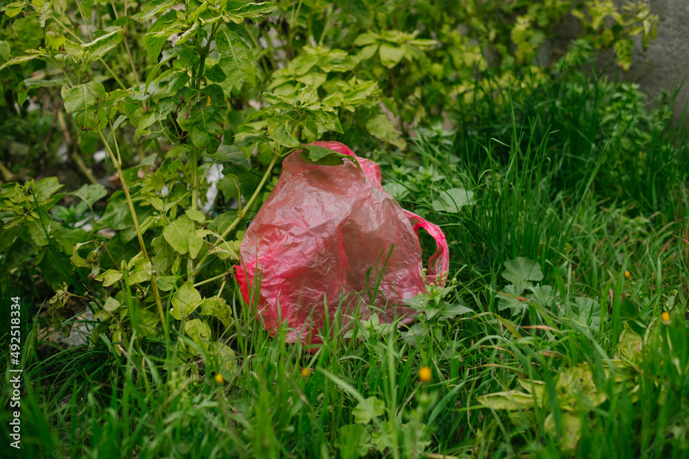 Garbage bag, a red garbage bag thrown into nature and a polluted ...