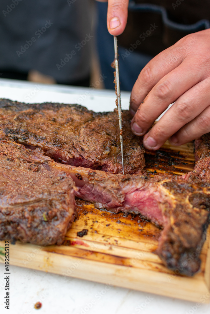 corte de res T- bone. T bone corte en el asador corte al carbón manos ...