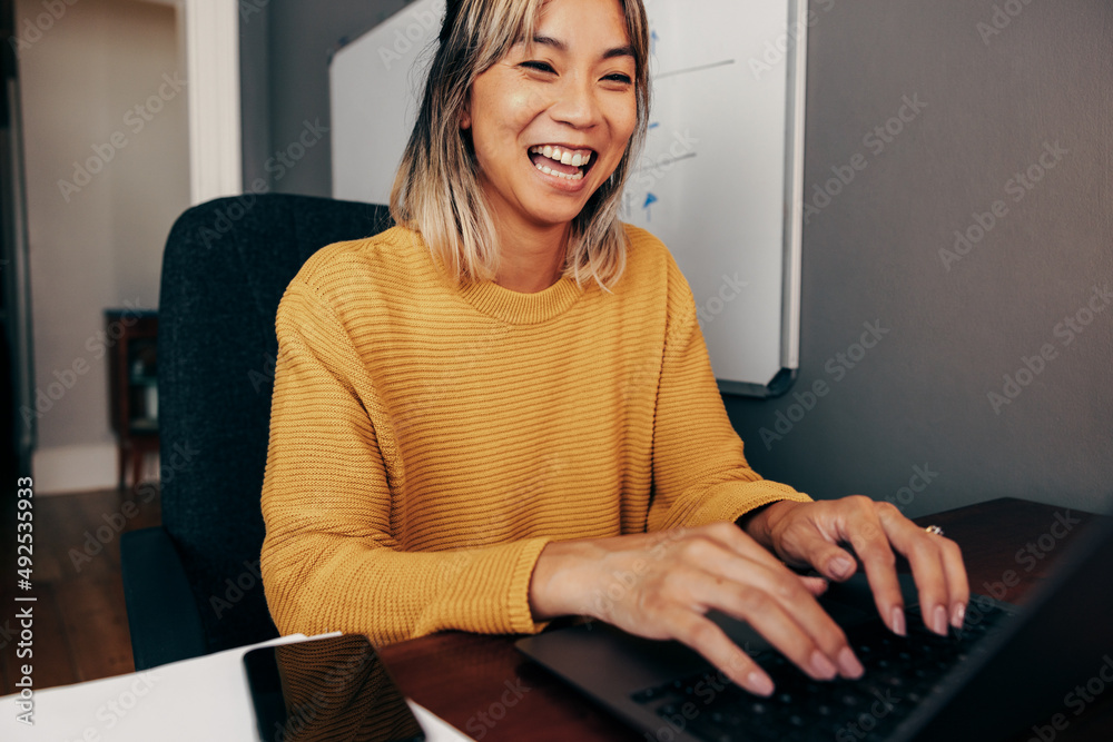Cheerful businesswoman typing an email in her home office Stock Photo ...