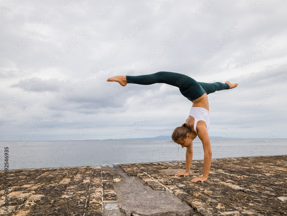 Outdoor yoga practice near the ocean. Young woman practicing Adho Mukha ...