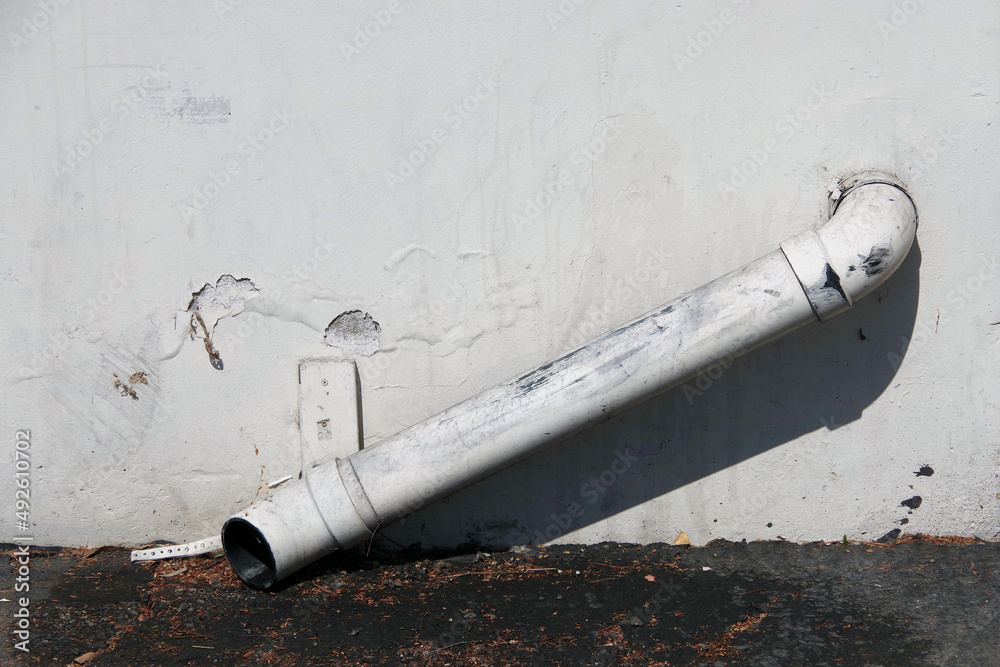Building wall with a rain drain pipe from an inner gutter downspout ...