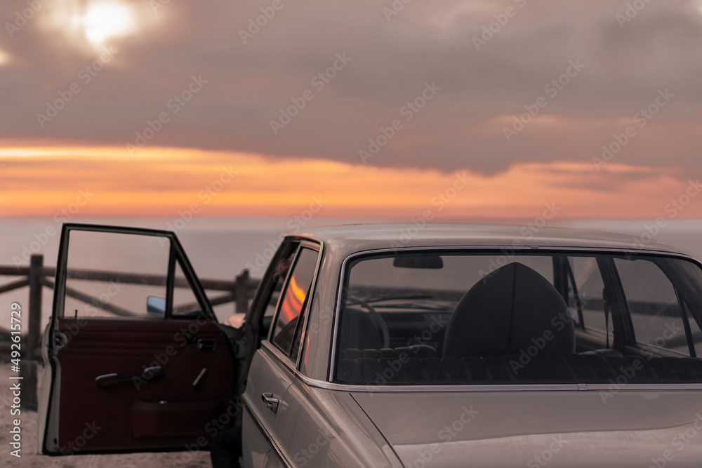 Vintage car parked with a surfboard inside in front of the ocean at the ...