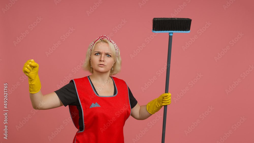 angry cleaning lady in an apron and gloves waving a broom on a colored ...