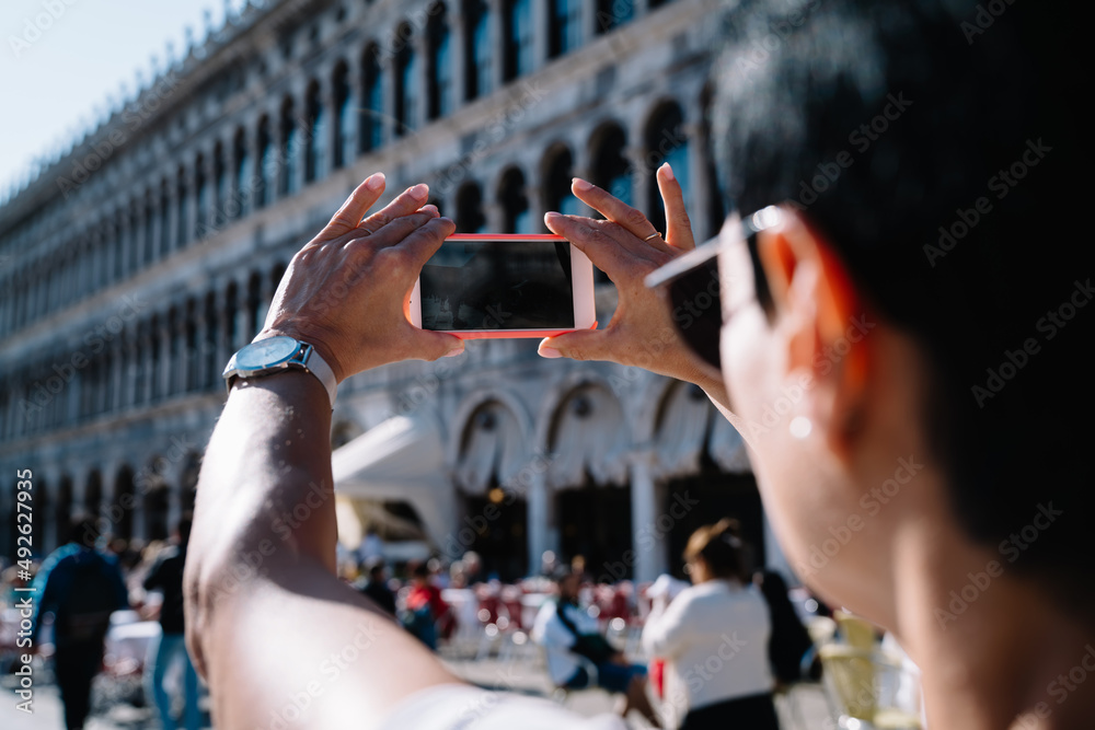 Cropped female tourist using cellular camera for photographing ancient ...