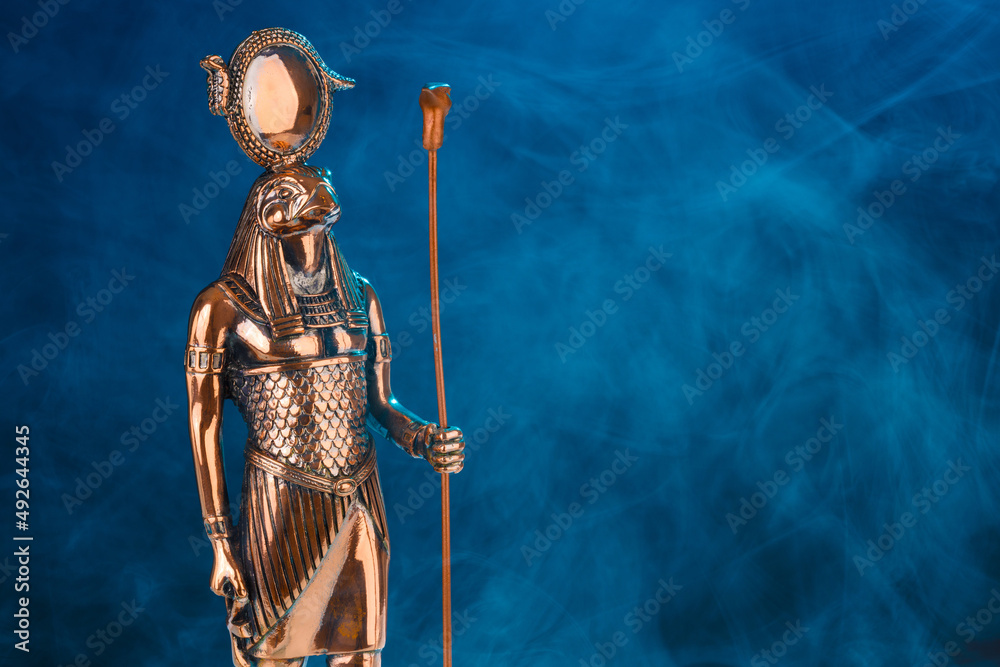 gold Egyptian figurine of the god RA with the head of a falcon in blue ...