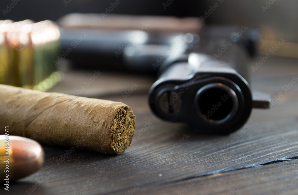 Gun with .45 bullets and a cigar on wooden background, gangster mafia ...