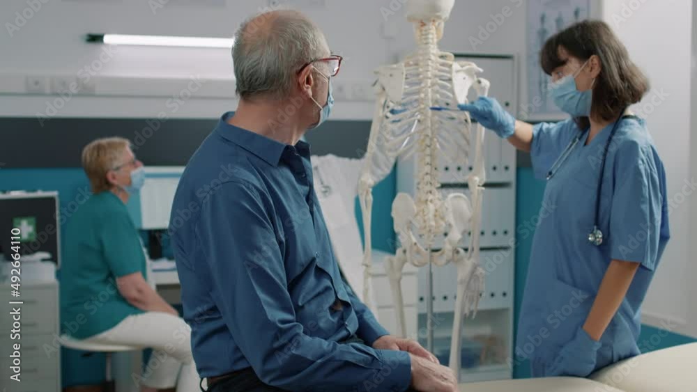 Female specialist pointing at spinal cord on human skeleton, explaining ...