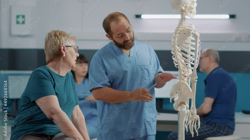 Male osteopath explaining back pain on human skeleton bones, doing ...