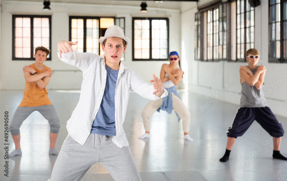 Teenage boy practicing hip hop moves with friends at group dance class ...