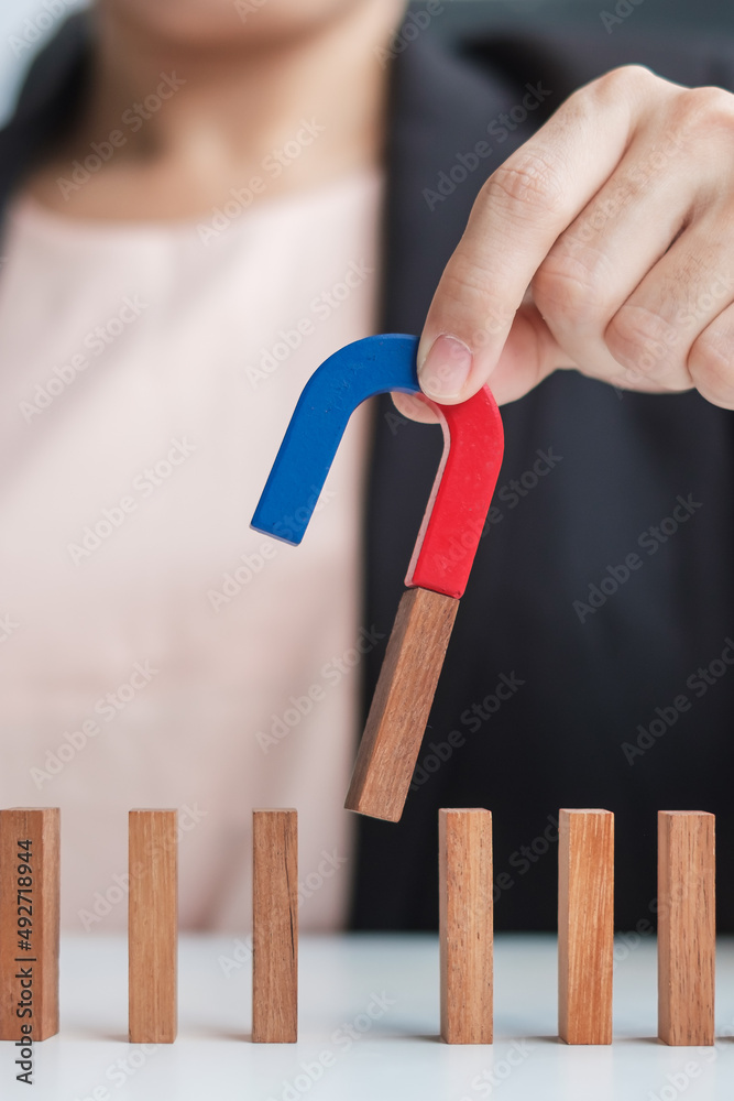 Business woman hand holding magnet and pulling man wooden figure from ...