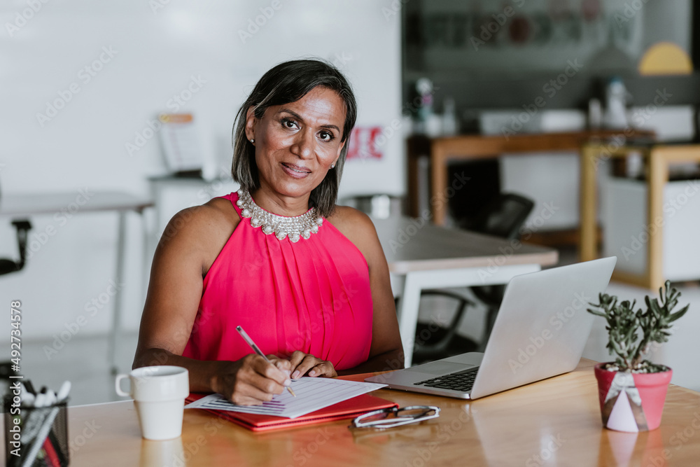 Latin transgender woman working with computer at the office in Mexico ...
