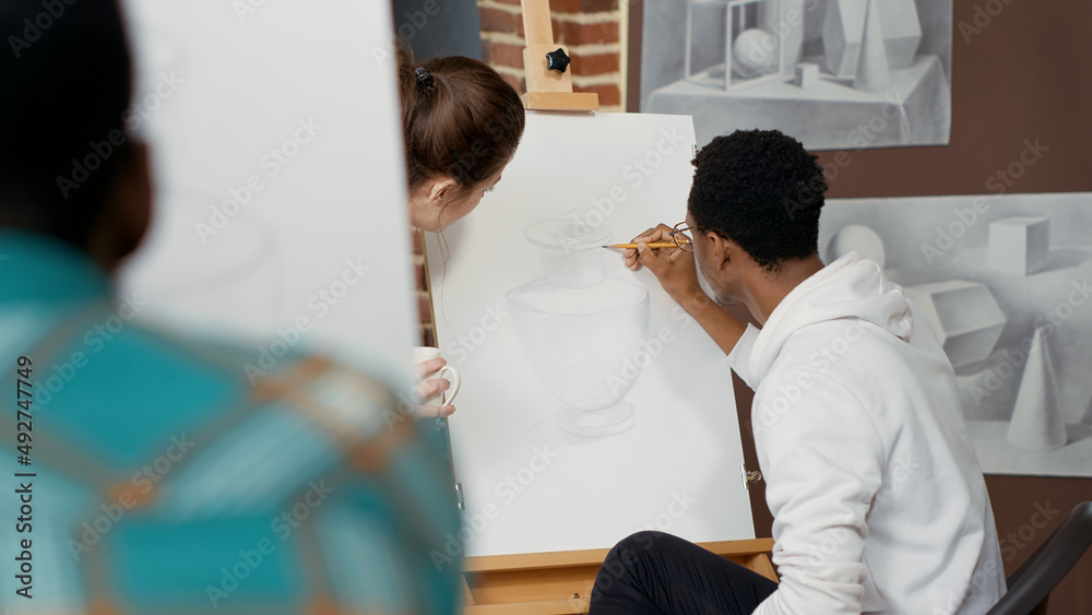 Young teacher talking to student about drawing design in creative ...