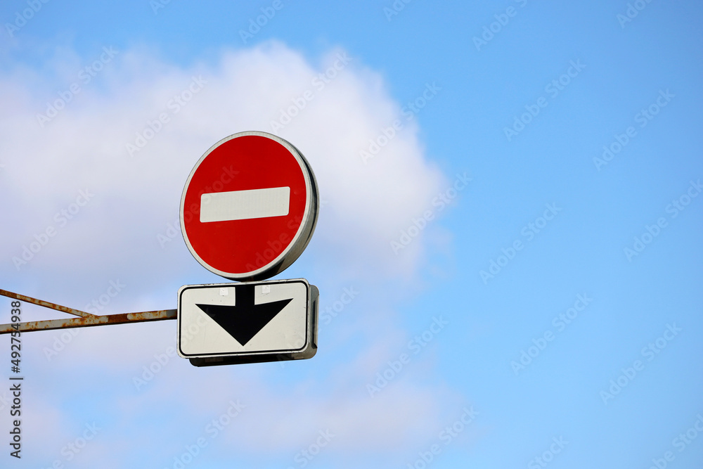 No entry sign and arrow down on background of blue sky with white ...