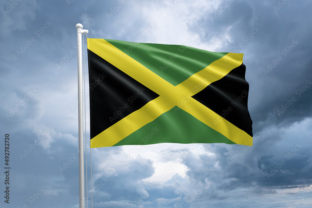 Jamaican flag on a flagpole waving in the wind on a cloudy sky ...