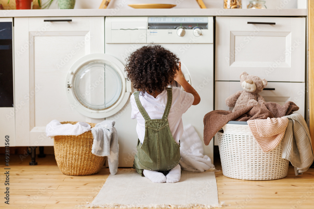 Unrecognizable child loading washing machine Stock Photo | Adobe Stock